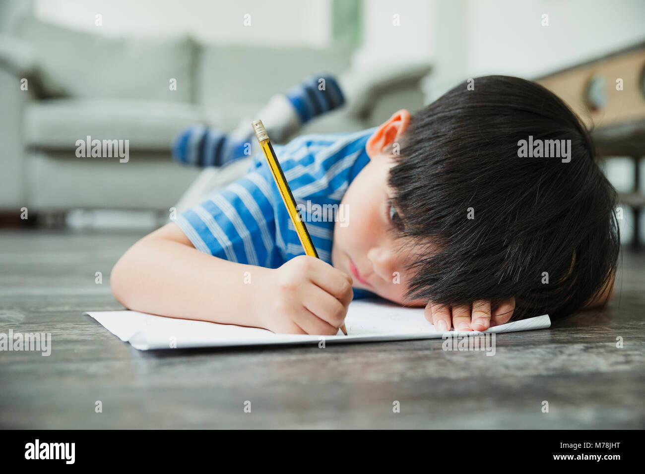 Little boy is lying on the floor, concentrating on his homework Stock ...