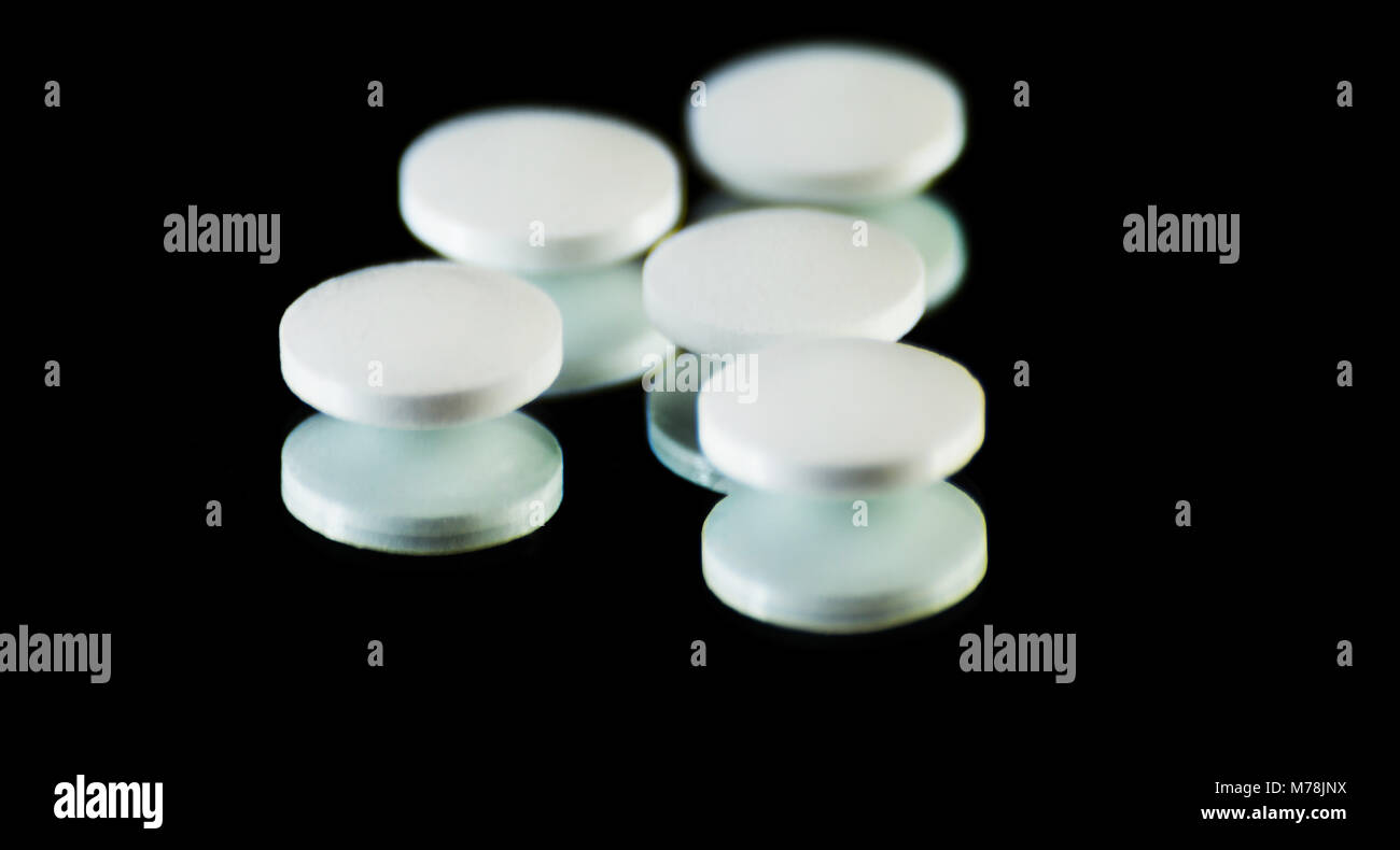 scattered tablets on a black background, pills reflected in the mirror ...