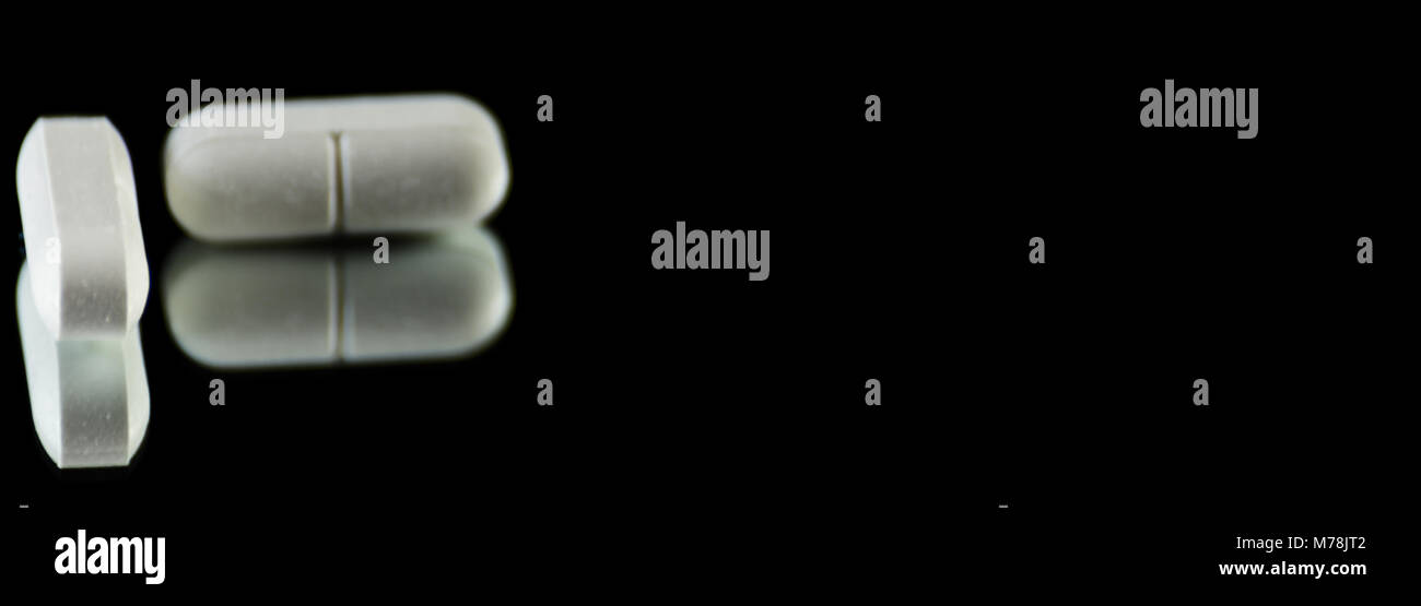 scattered tablets on a black background, pills reflected in the mirror ...