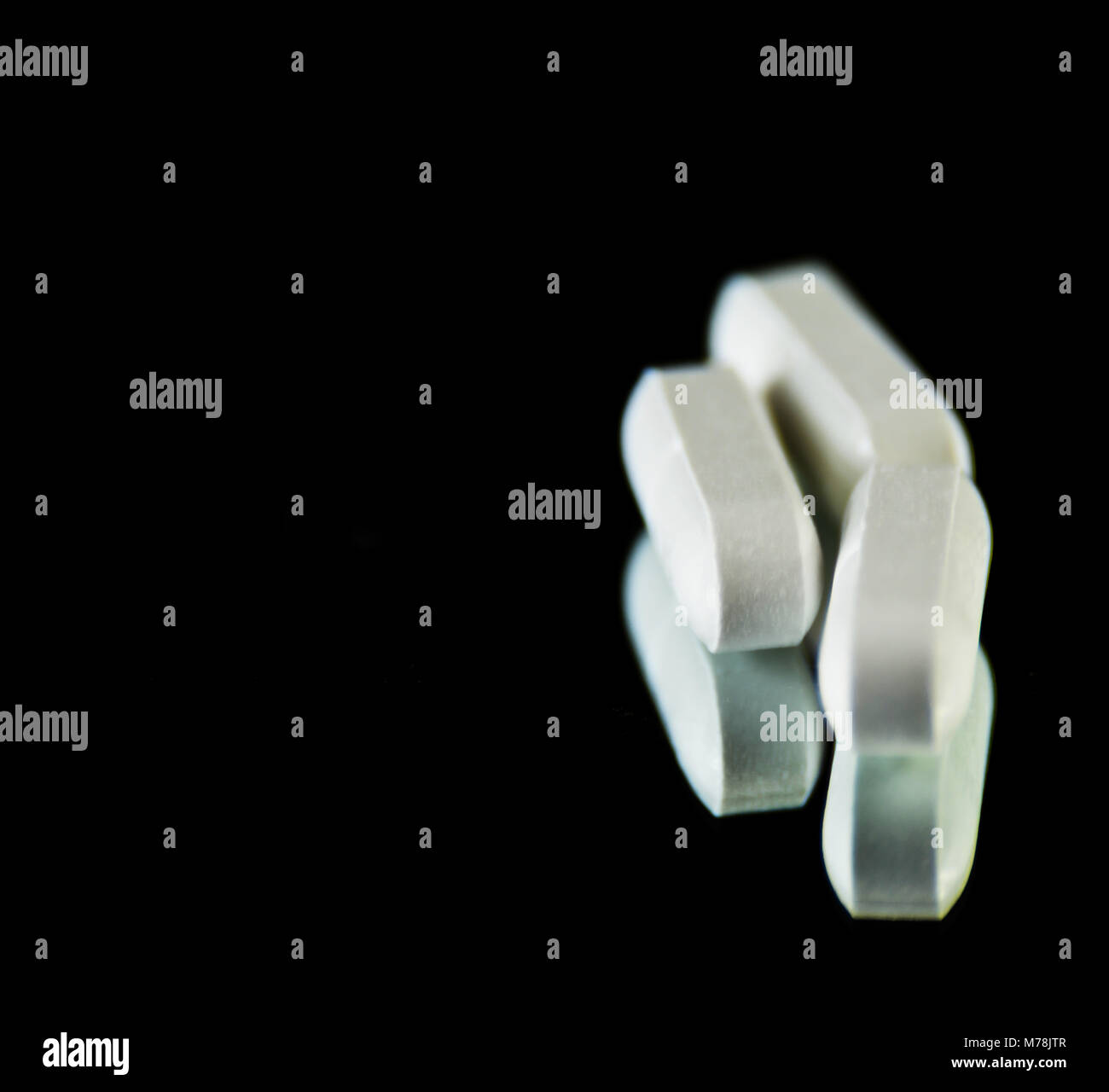 scattered tablets on a black background, pills reflected in the mirror ...