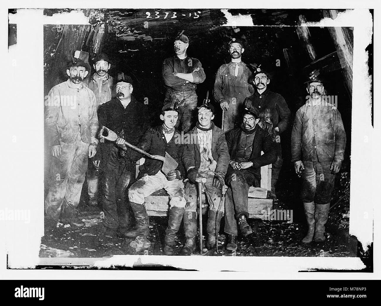 The photograph shows a group of coal miners, reflecting the labor ...