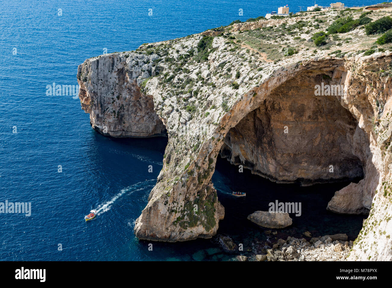 Boats of tourists visiting the dramatic natural arch at the Blue Grotto ...