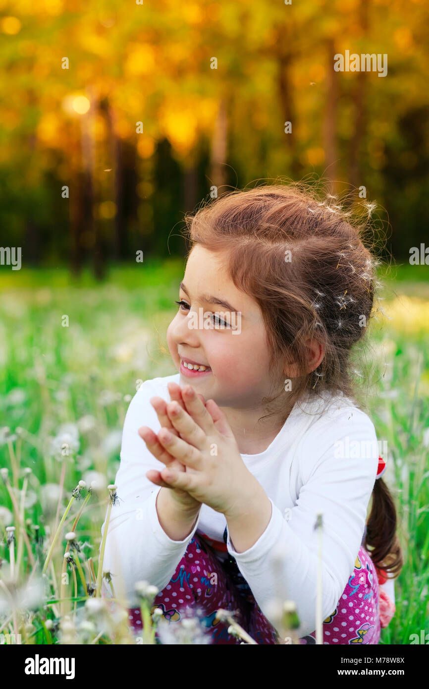 Beautiful little child smiling with dandelion flower in summer park at ...