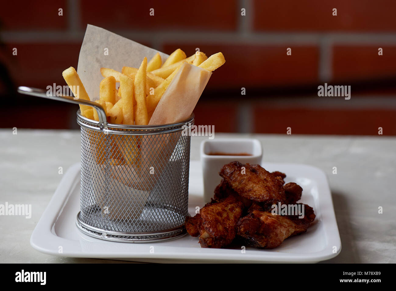 Chicken wings with sauce ketchup and fries in a metal stand on ...