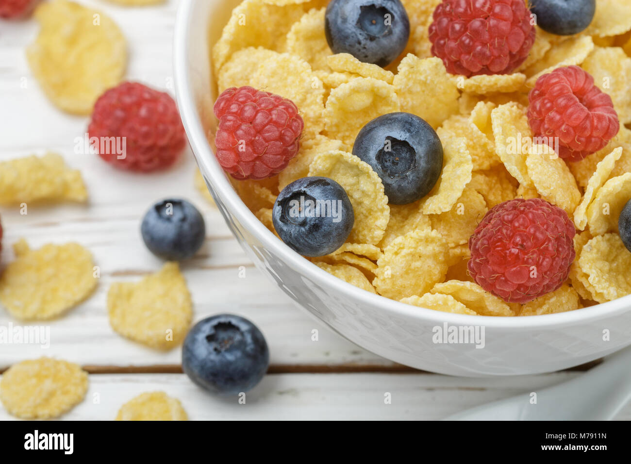 Cornflakes with fresh berries raspberry and blueberry in white bowl on ...