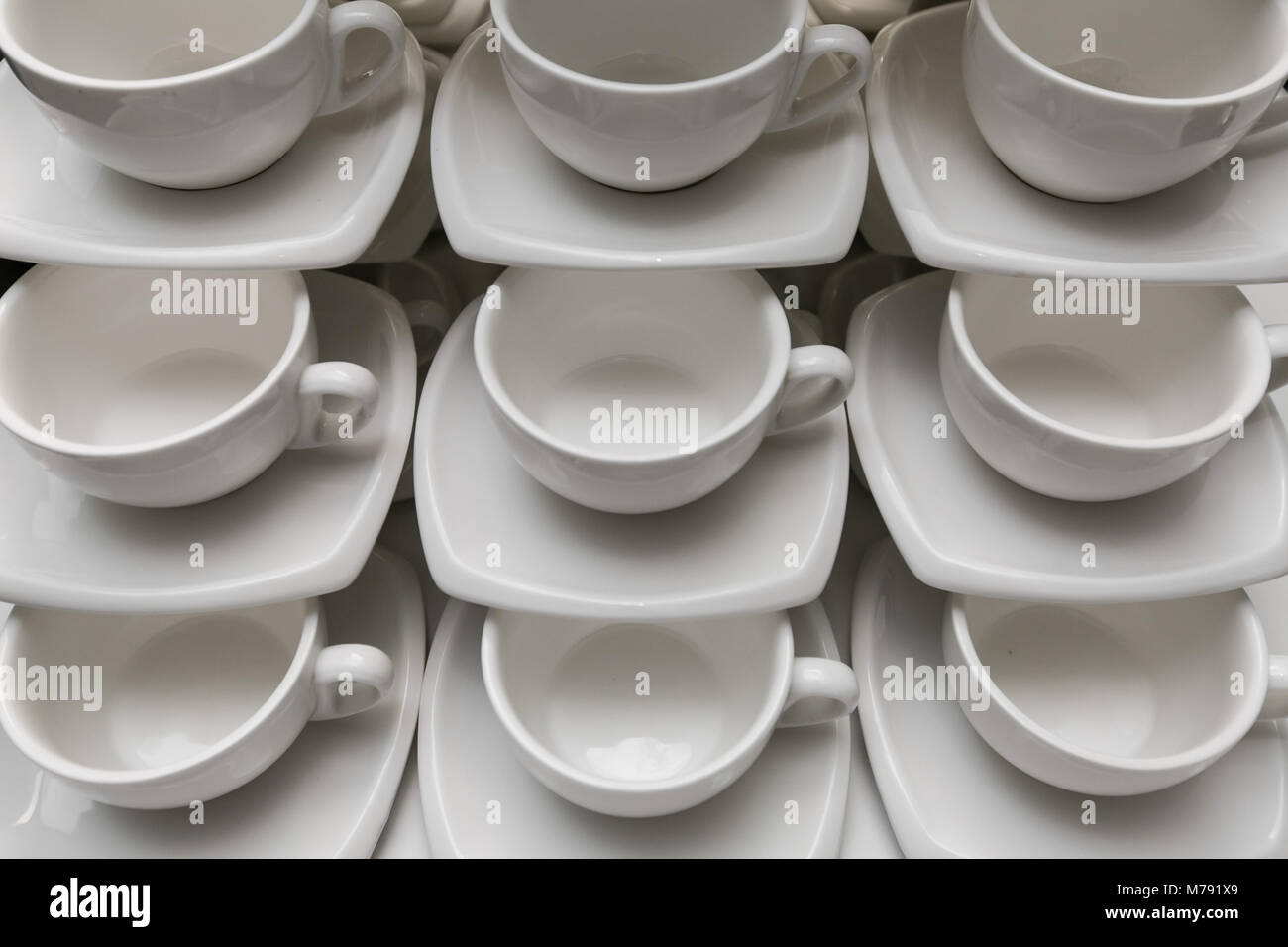 Many rows clean white coffee cup, tea spoon and saucer on table. Empty ...