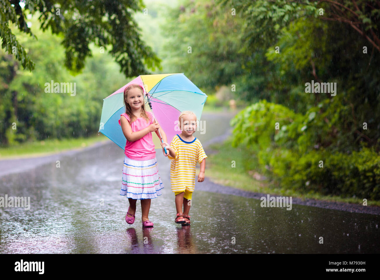 Kids playing out in the rain. Children with umbrella play outdoors in ...