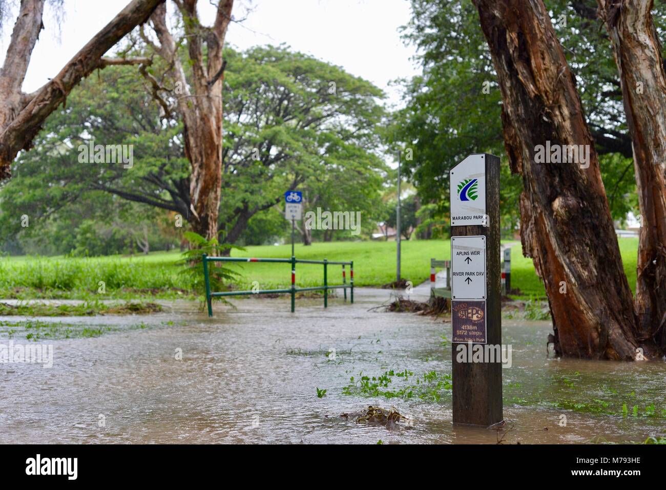 Debris and flood waters lie over a pedestrian path after storms and ...