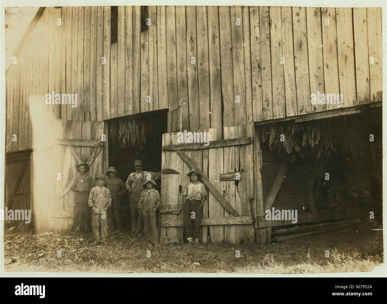 The photograph depicts the barn of Daniel Barrett, showing a group of ...