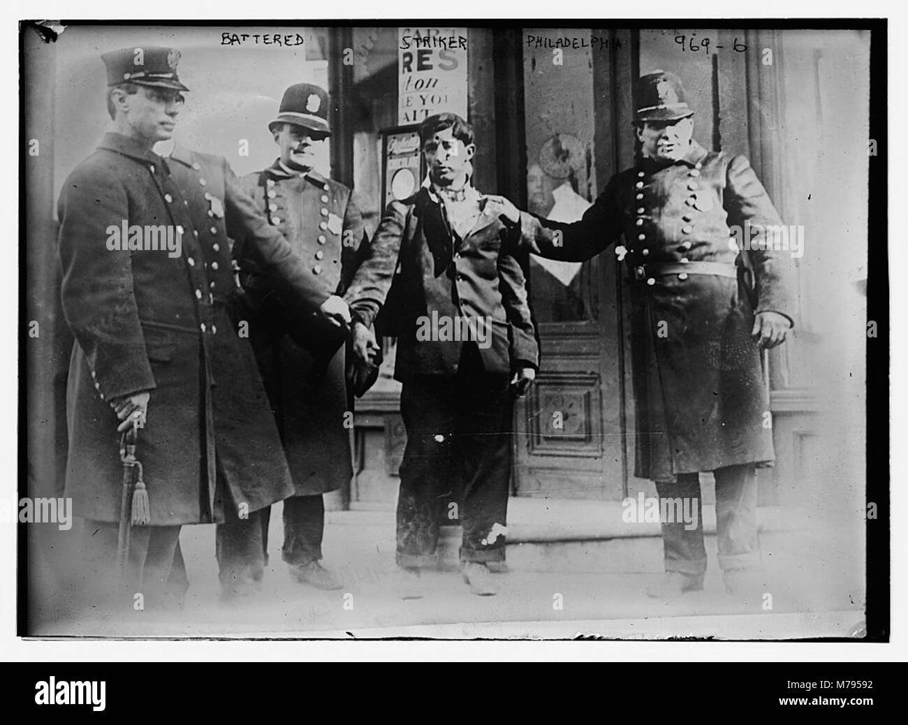 This photograph captures a scene of a battered striker alongside police ...