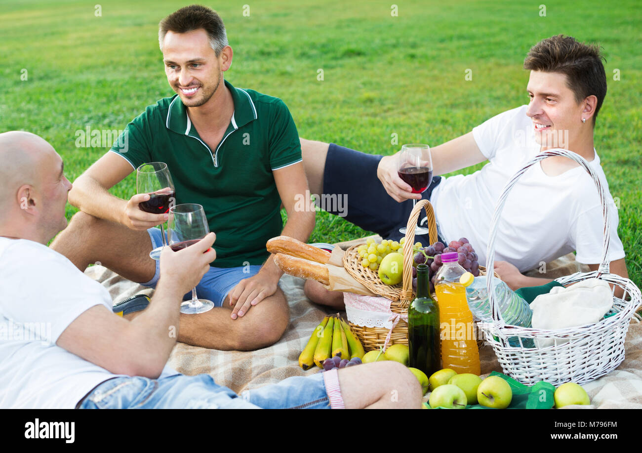 Three happy men friends having fun on picnic outdoors together Stock ...