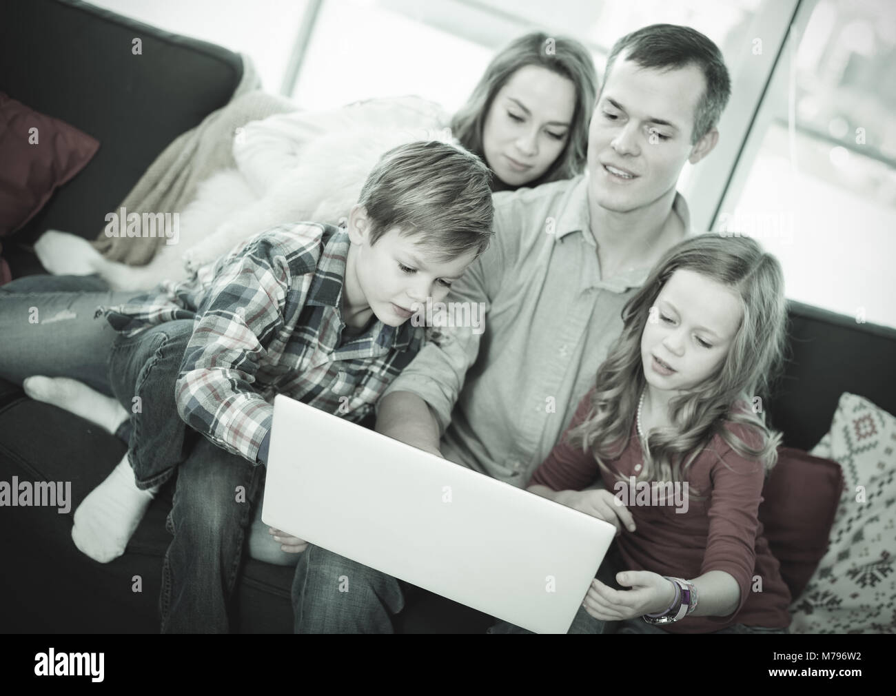 positive family watching movie on laptop together at home on the couch ...
