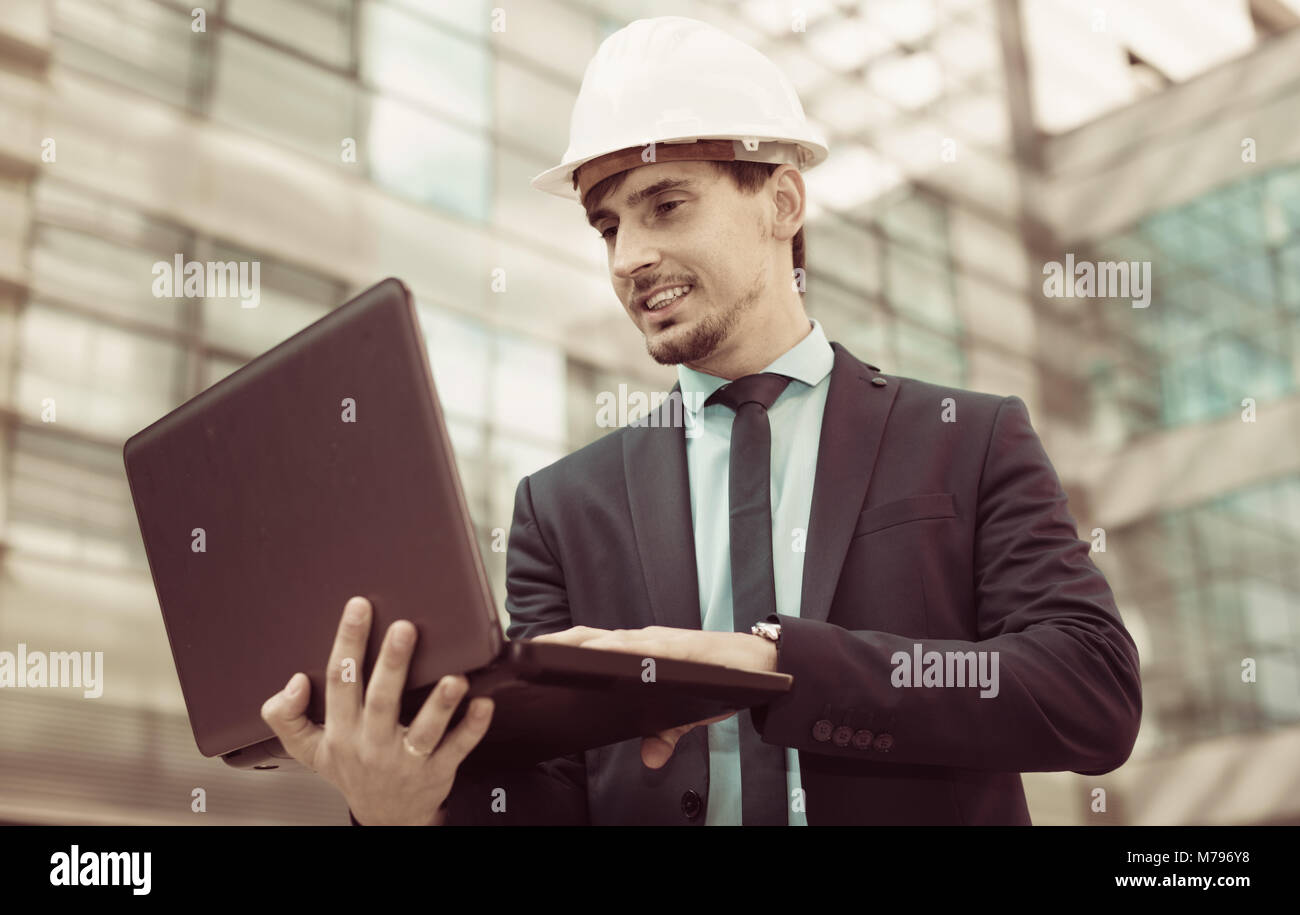 Positive smiling professional man in jacket and helmet working at ...