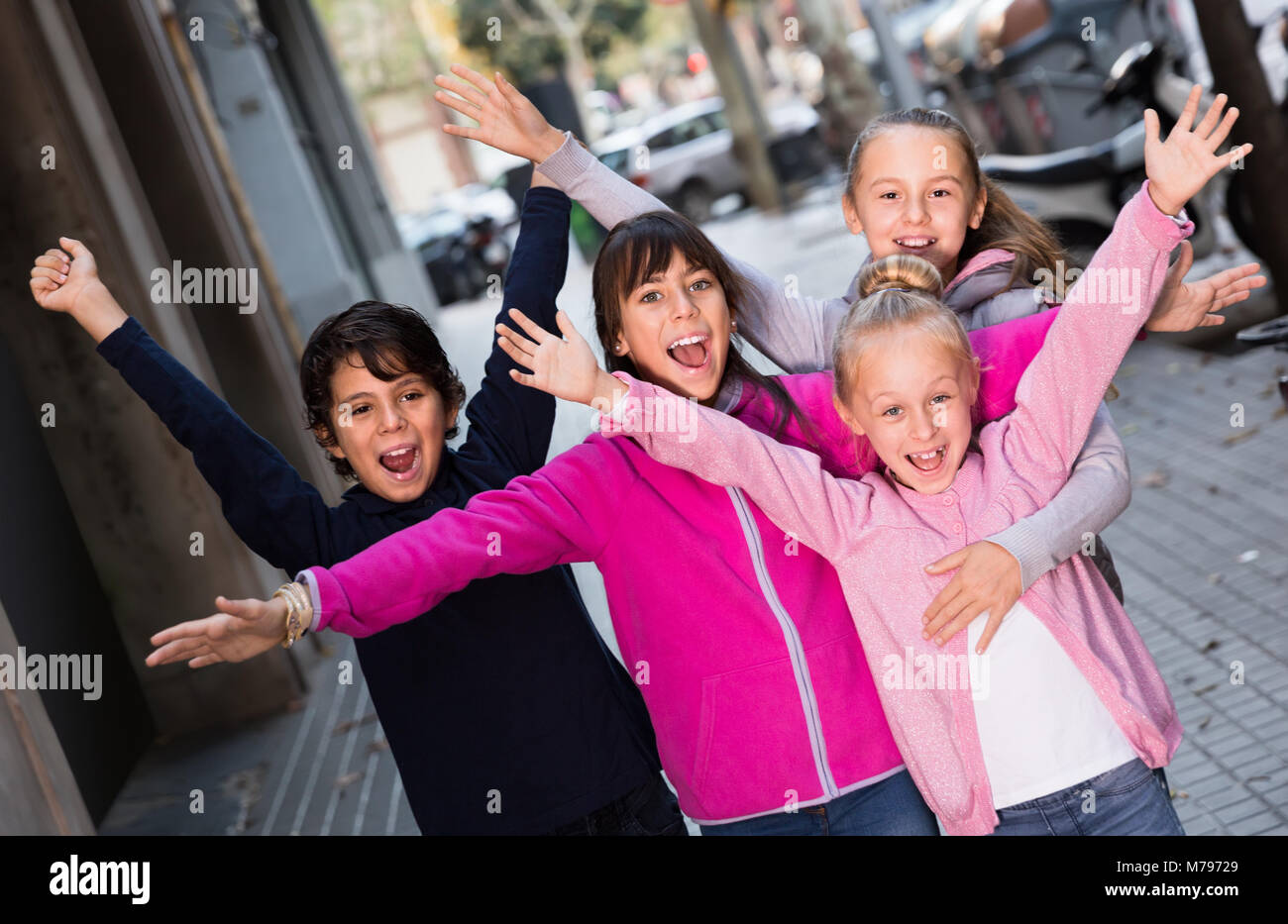 four cheerful children play without parents in street on sidewalk in ...