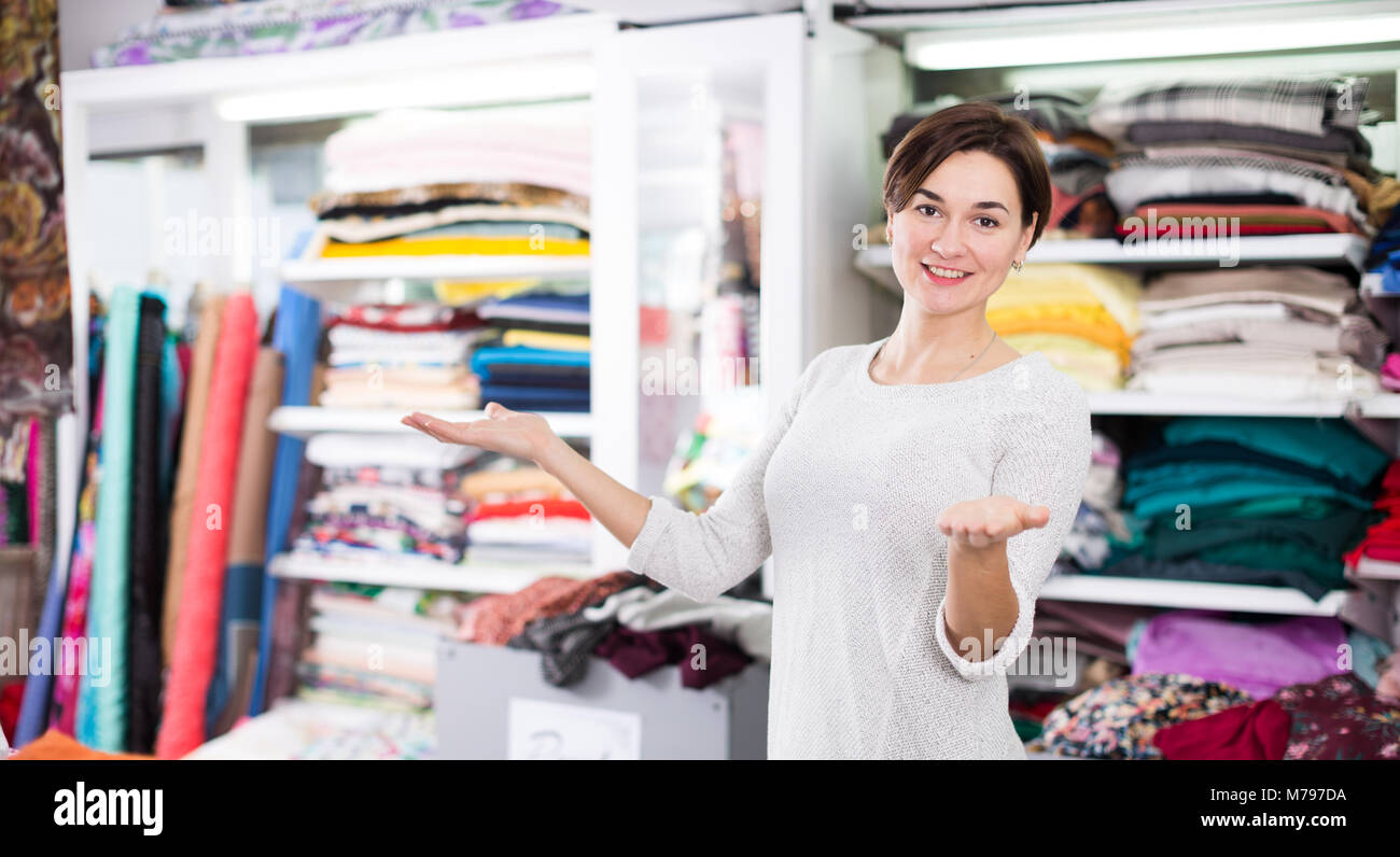 Young woman seller displaying various fabrics at drapery shop Stock ...