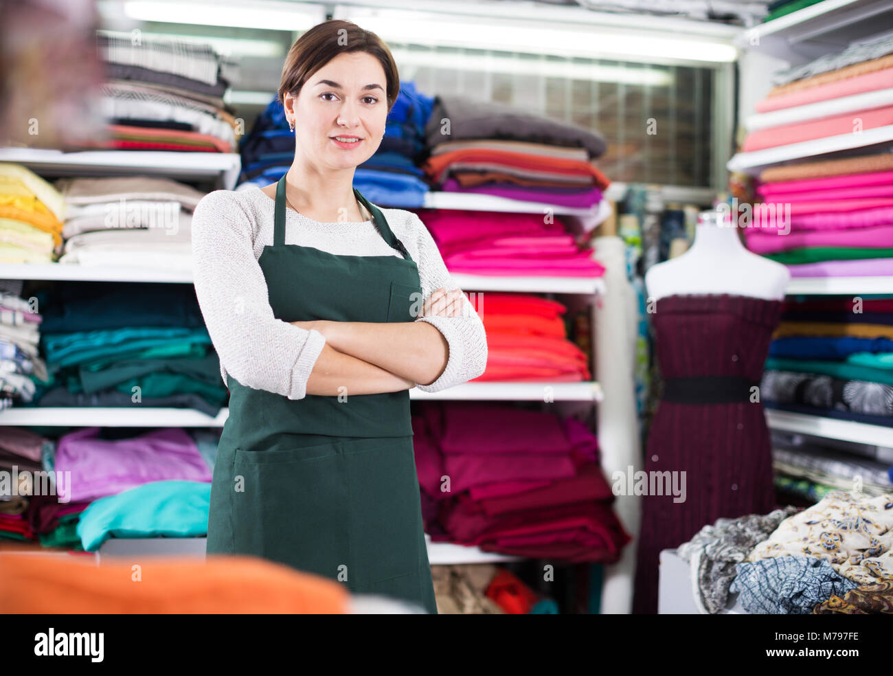Smiling girl seller showing wide assortment at drapery shop Stock Photo ...