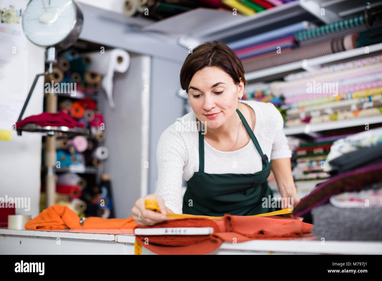 Female shop assistant measuring piece of cloth at drapery shop Stock ...