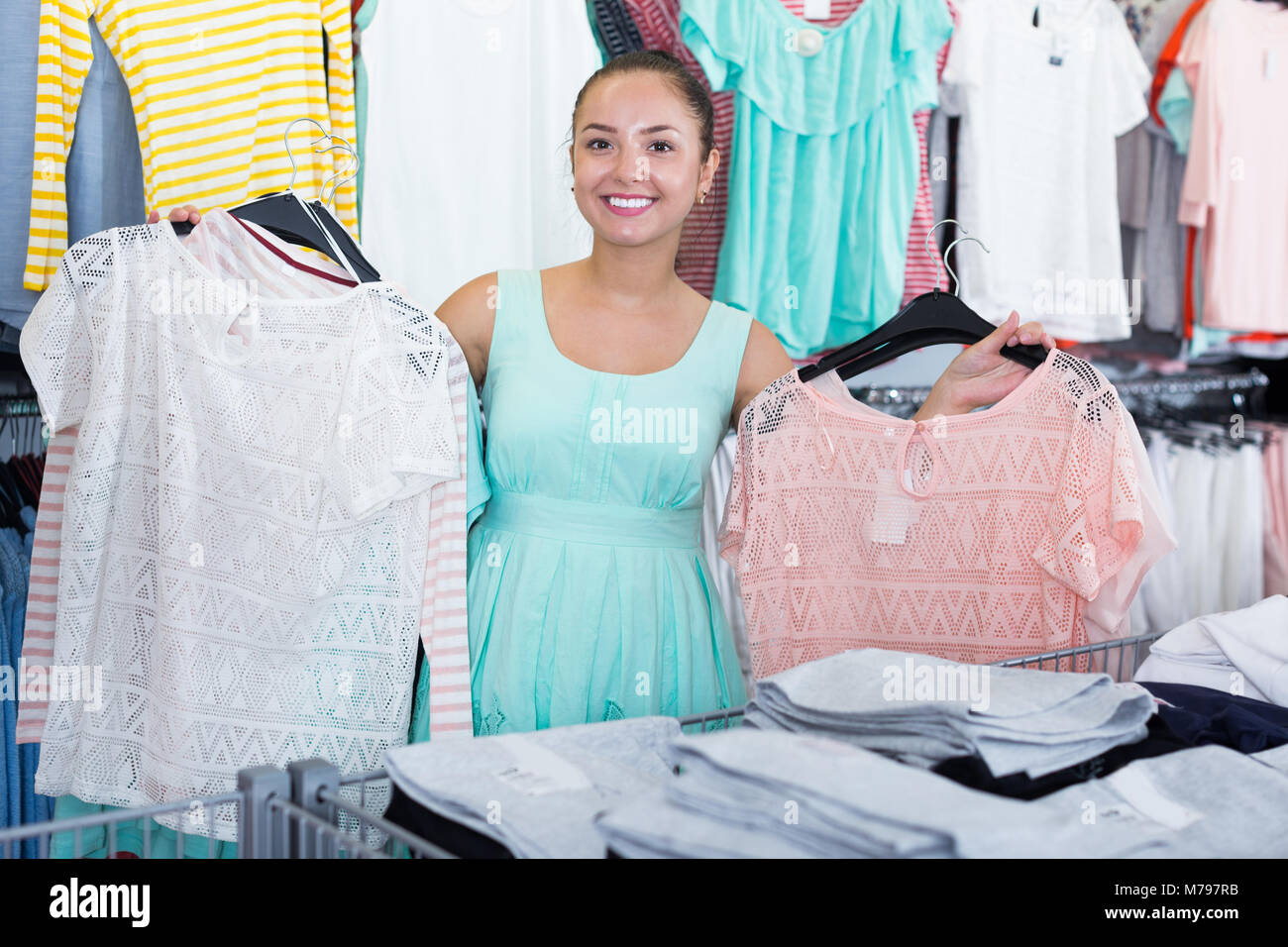 Young woman shopper choosing new garments at fashion shop sales Stock ...