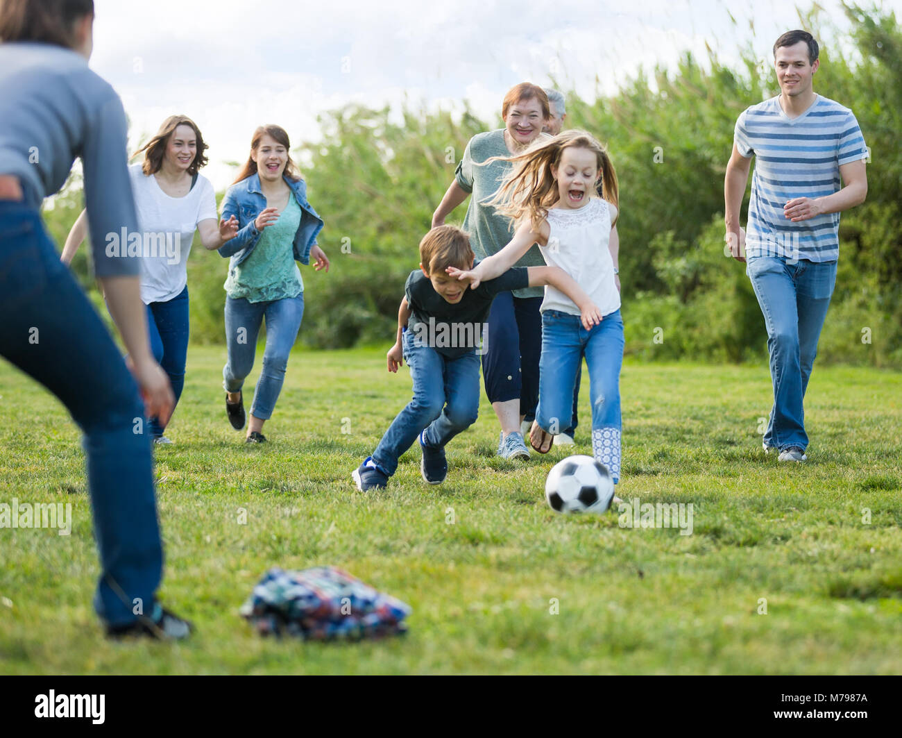 Smiling people of different ages playing football on grass Stock Photo ...