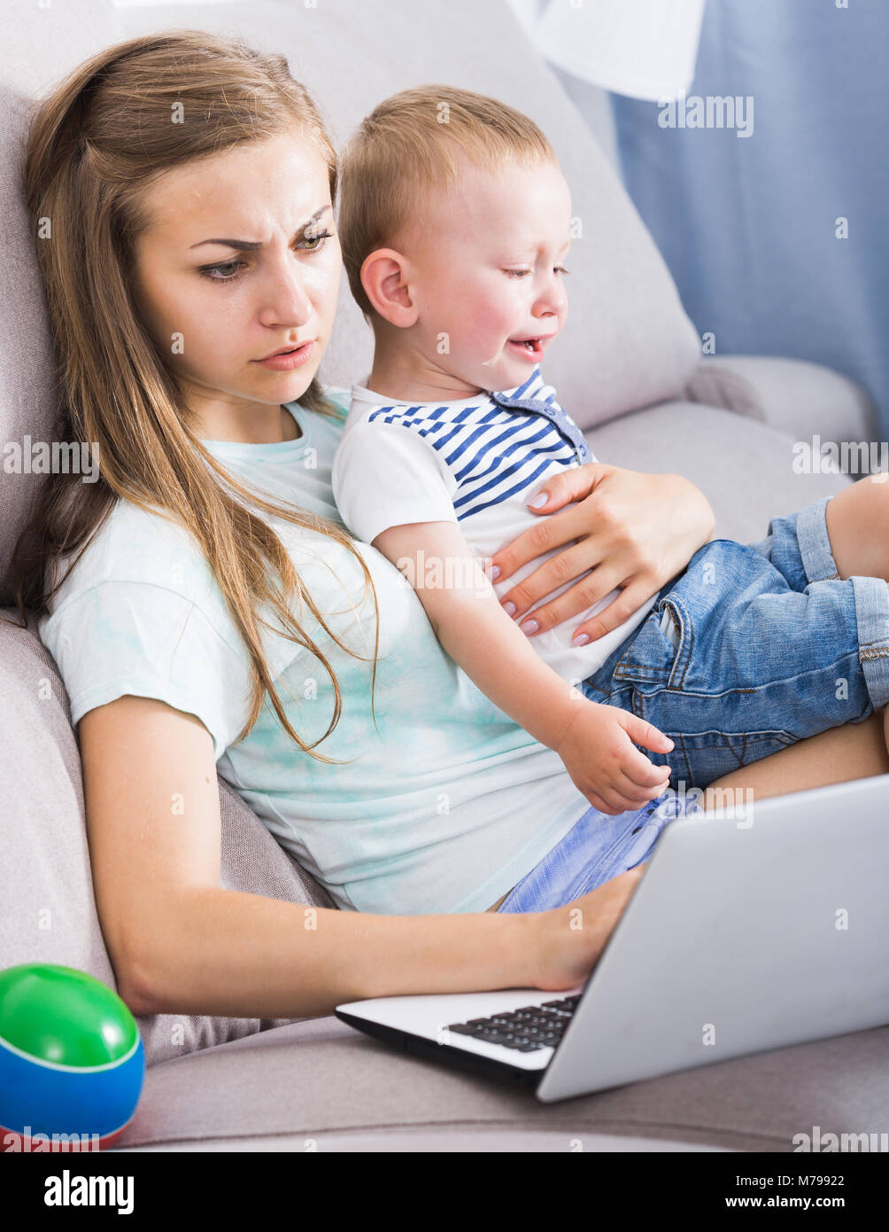 Perplexed woman is having issue with work while kid crying at home ...