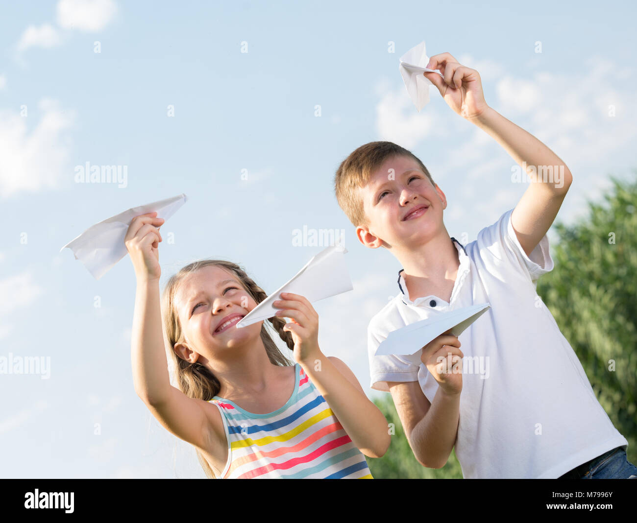 Two smiling kids playing with flying paper planes outdoors Stock Photo ...