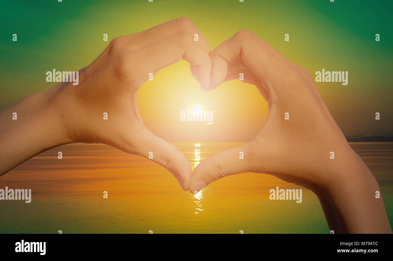 Silhouettes hand heart shaped with sunset and sea background. Vintage ...