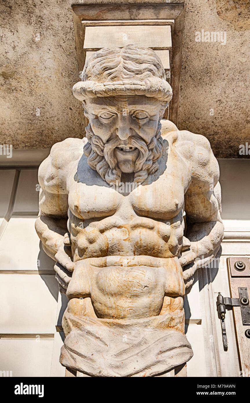 Architectural detail of a heavily muscled man that is carved of stone ...