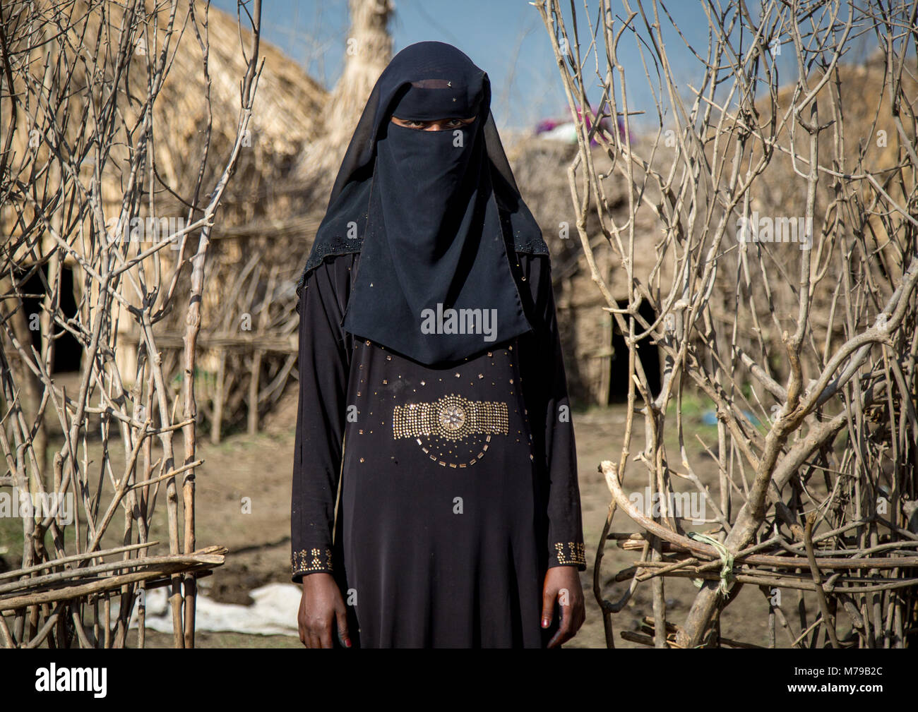 Oromo veiled woman with a burqa standing in front of her village ...