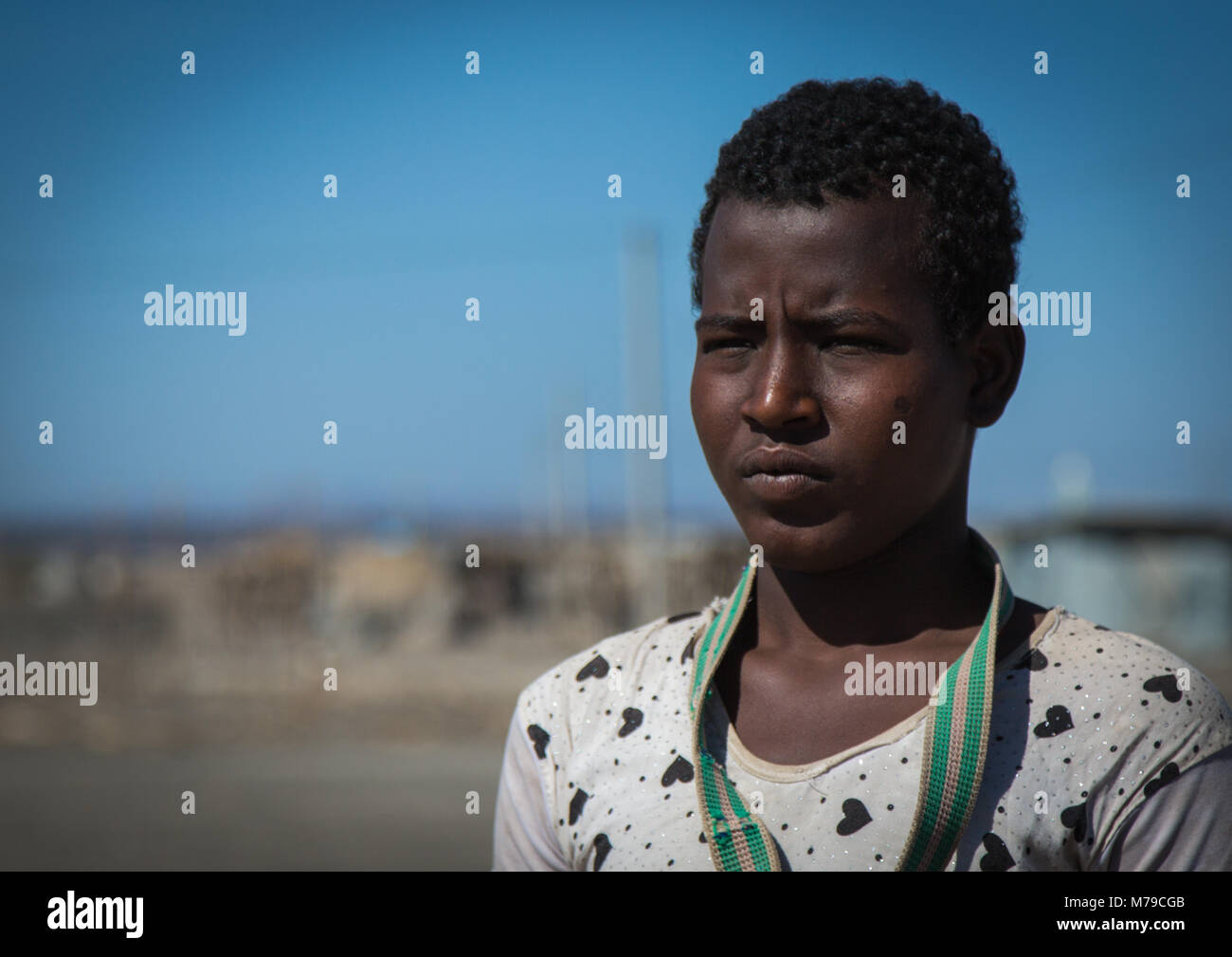 Portrait of an afar tribe boy with a belt as necklace and a fancy tee ...