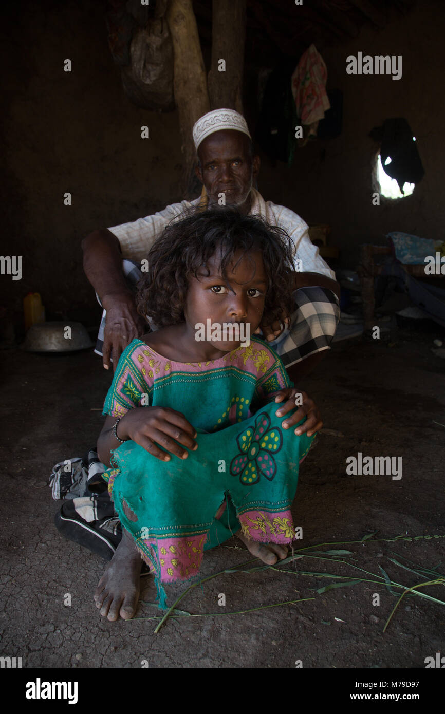 Portrait of an afar tribe man and his little girl inside their hut ...