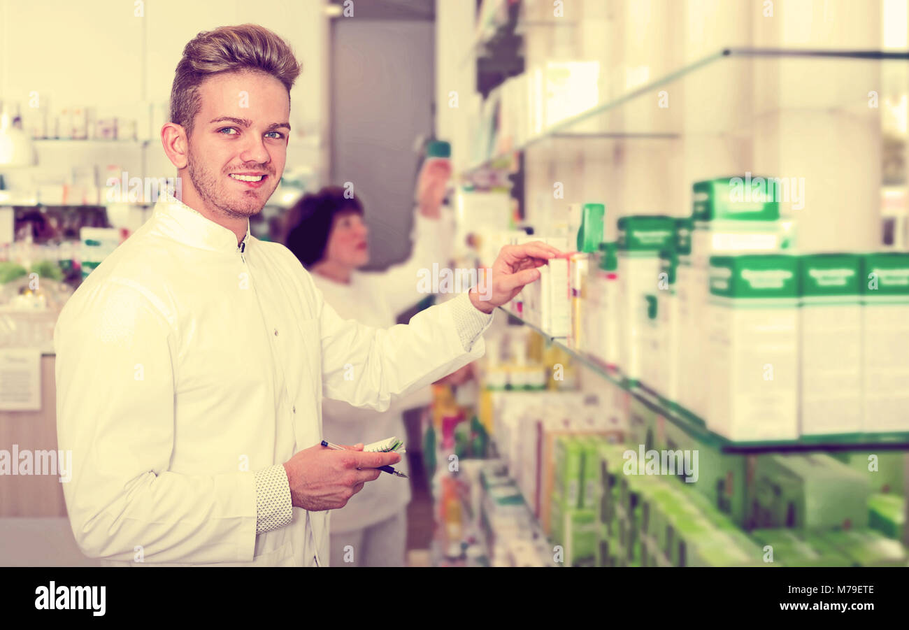 Portrait of cheerful man druggist in white coat giving advice to ...