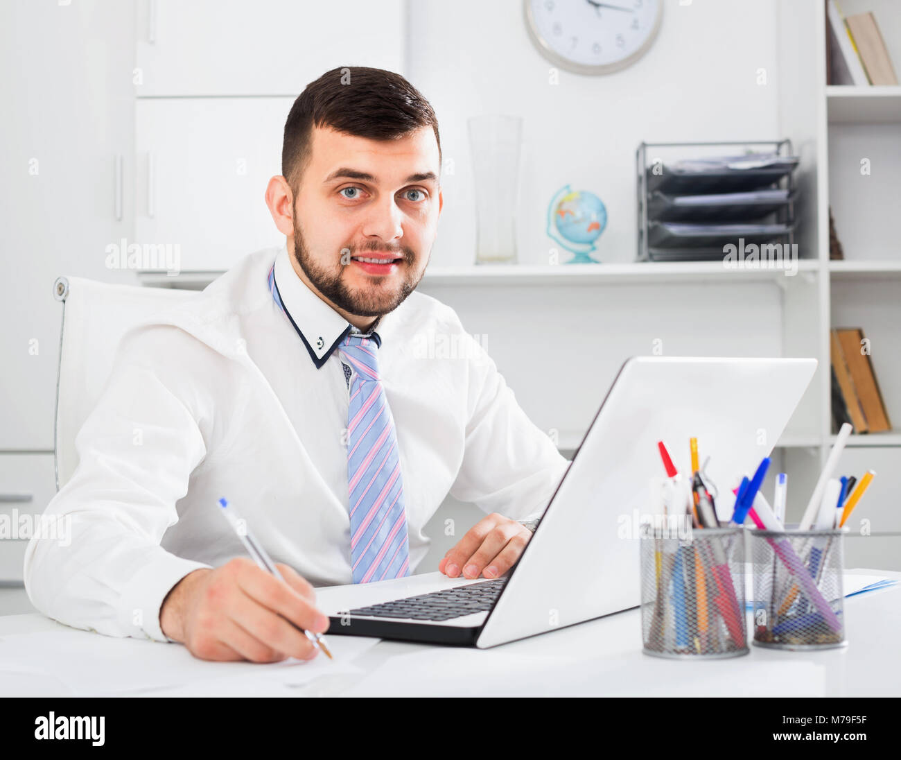 Young happy cheerful positive male worker working productively on ...