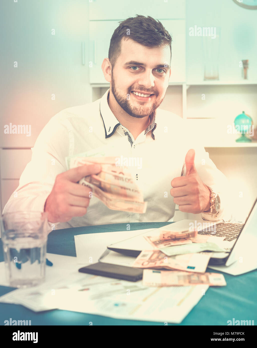 Young cheerful positive male businessman earning money easily online in ...