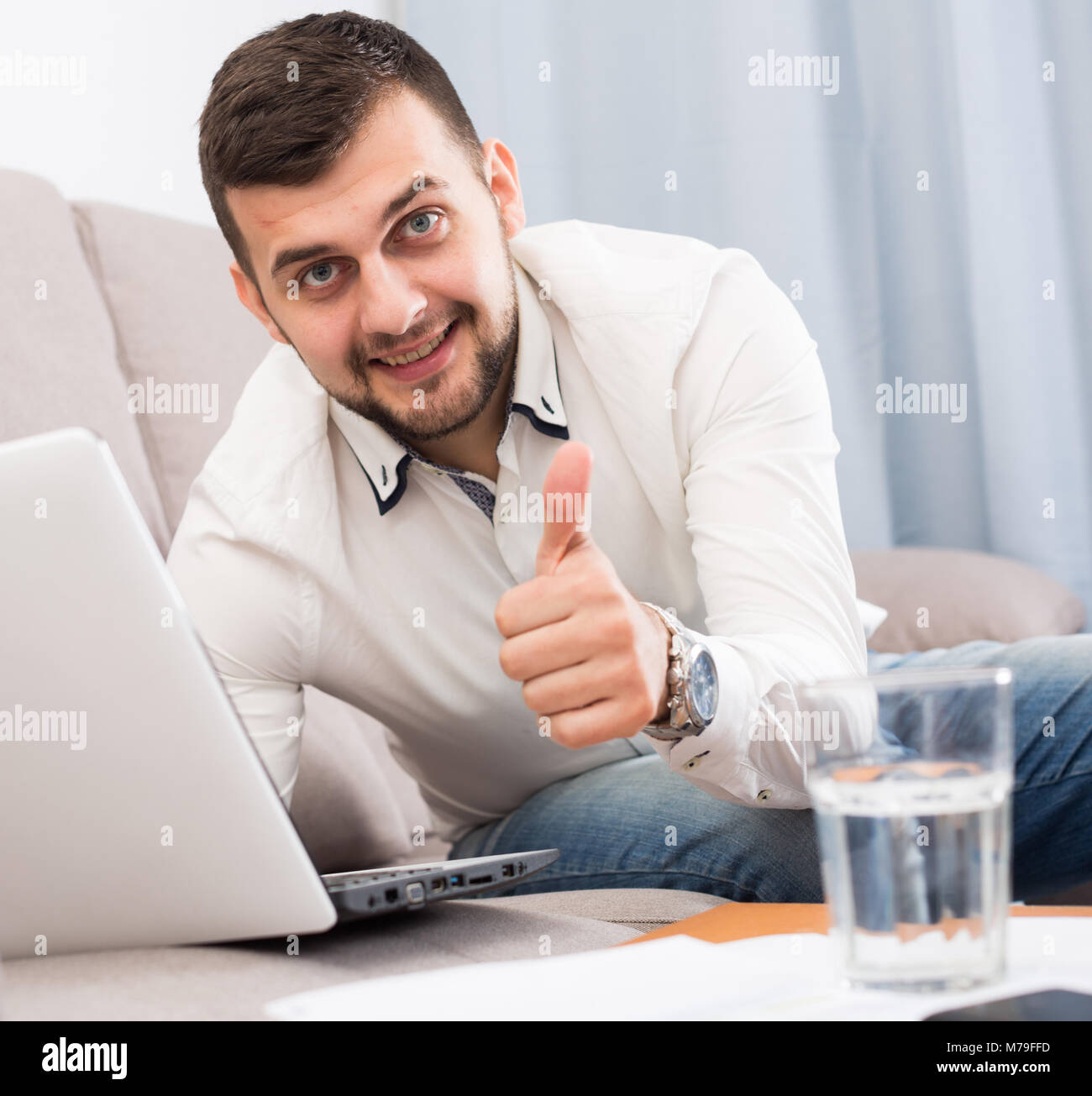 Smiling young man happy to book hotel online at home Stock Photo - Alamy