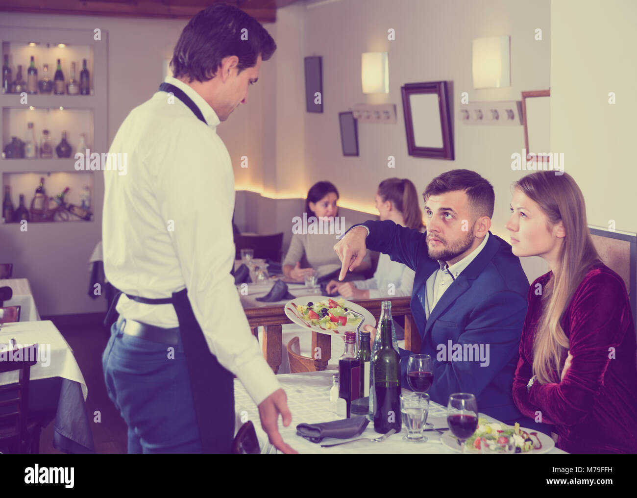 displeased guests conflicting with waiter because of poor quality of ...