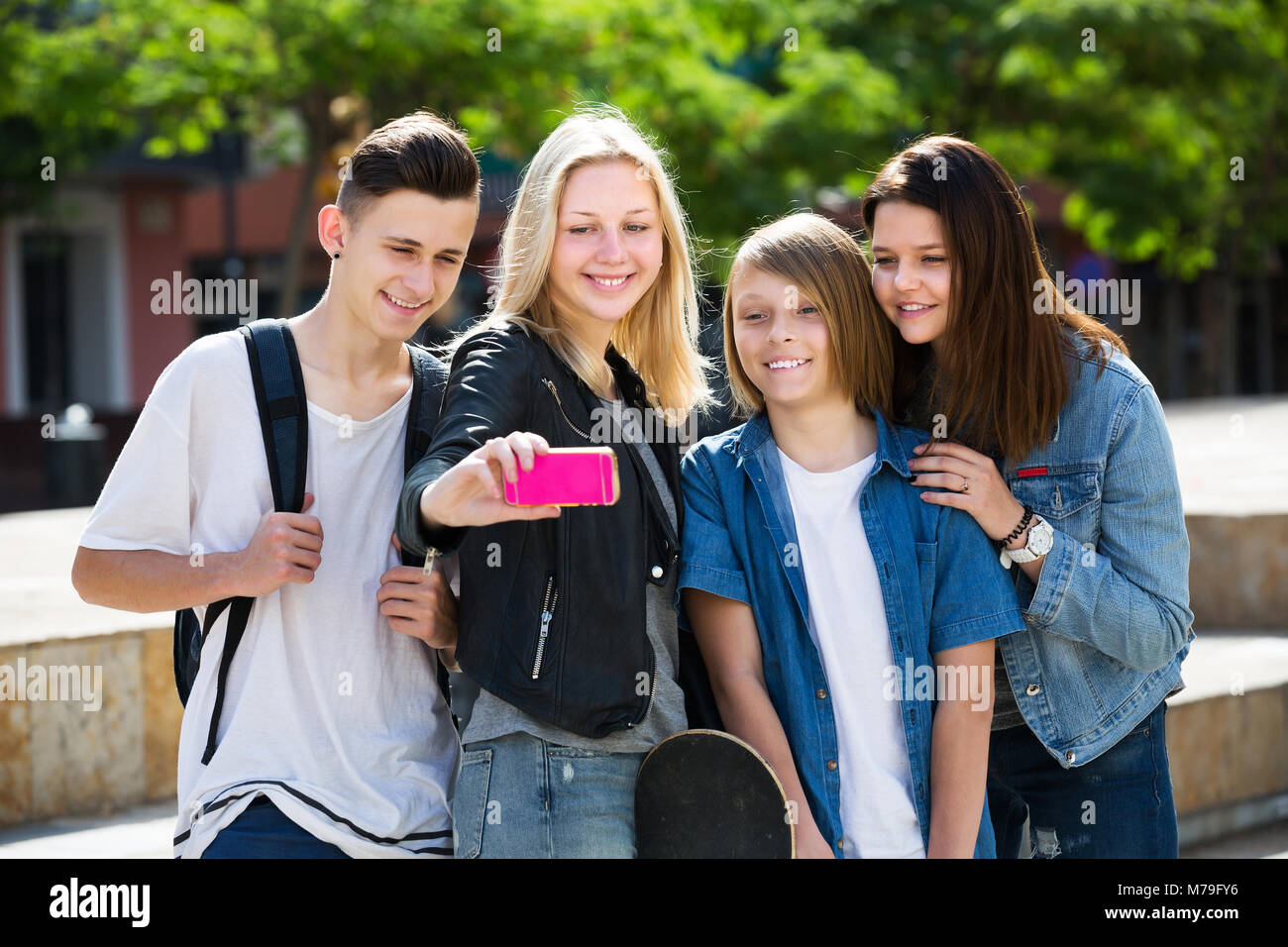 Group of smiling young teenagers taking mobile self picture with phone ...