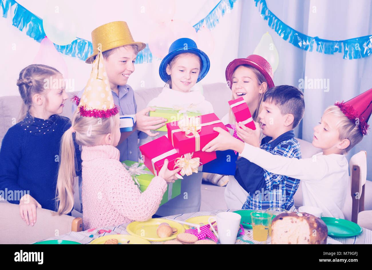 Cheerful children presenting gifts to girl during birthday party Stock ...