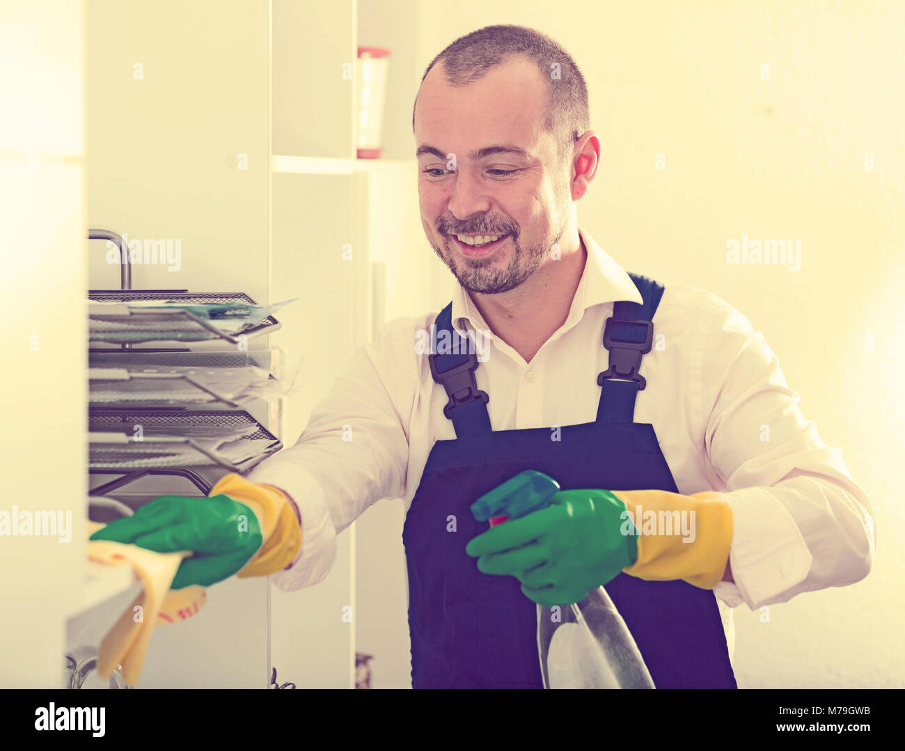 Young happy european businessman in office dusting surfaces in latex ...