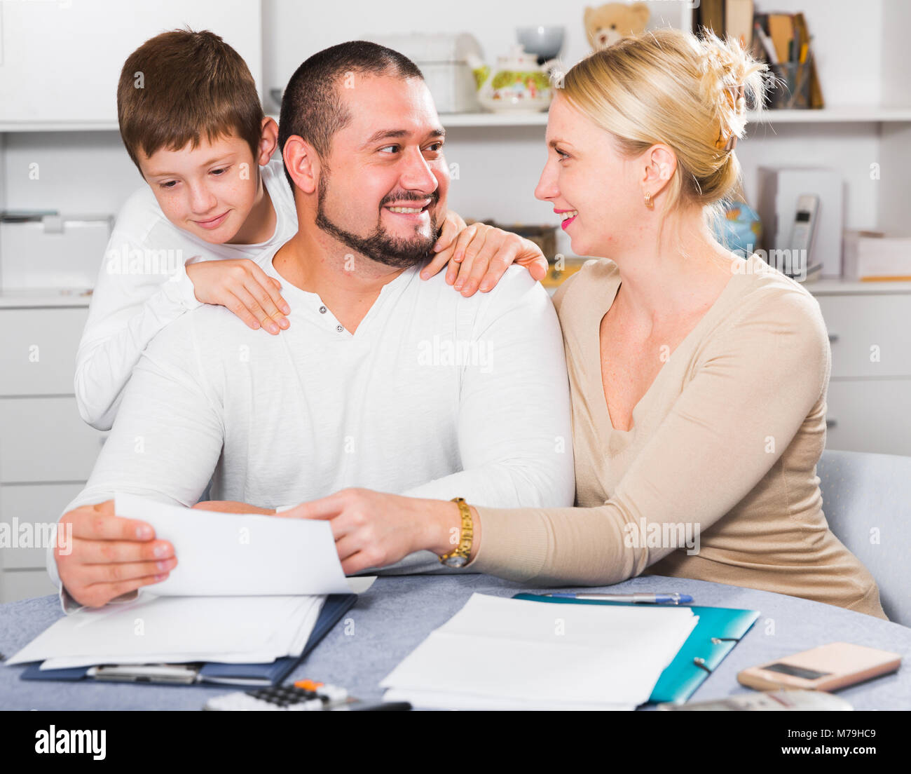 Portrait of happy parents with son looking at documents at home Stock ...