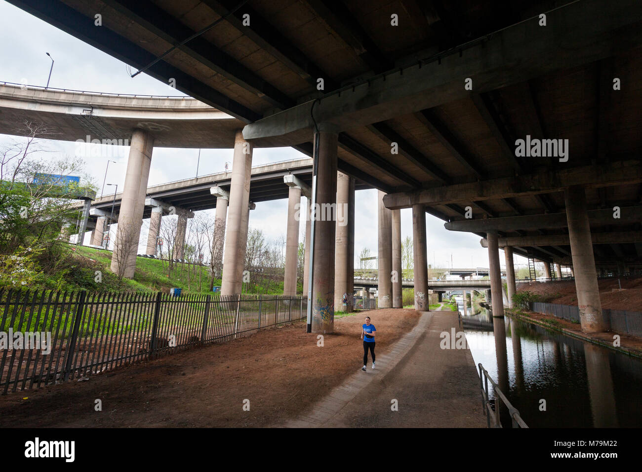 A jogger running along the canal towpath beneath the Spaghetti Junction ...