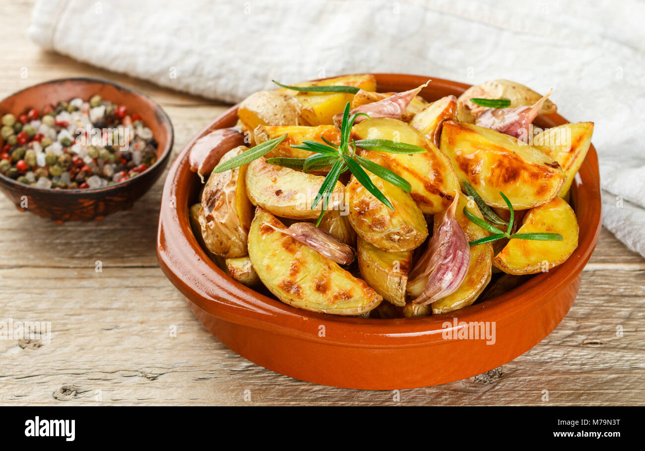 Potato wedges baked with garlic, rosemary and spices in a ceramic form ...