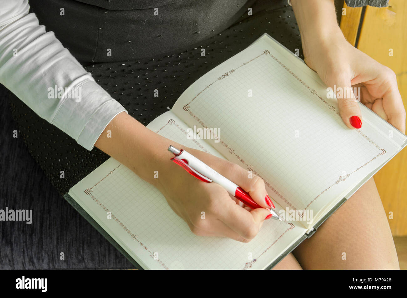 Business woman hand is writing on notepad with pen in an empty lecture ...