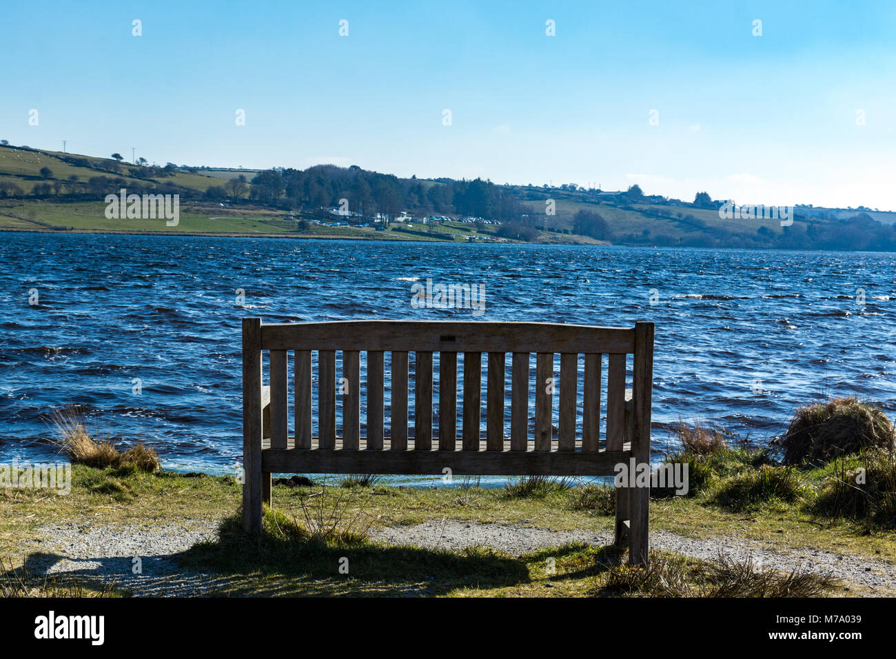 An empty bench with an onlooking view of Siblyback Lake in Cornwall, UK ...