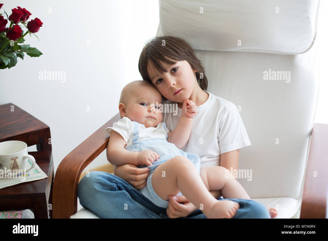 Adorable preschool child, hugging his baby brother in rocking chair ...