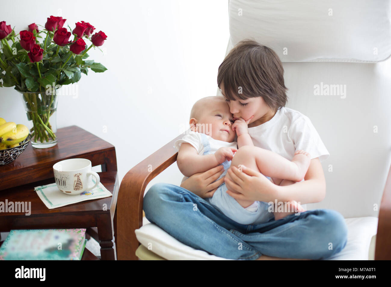 Adorable preschool child, hugging his baby brother in rocking chair ...