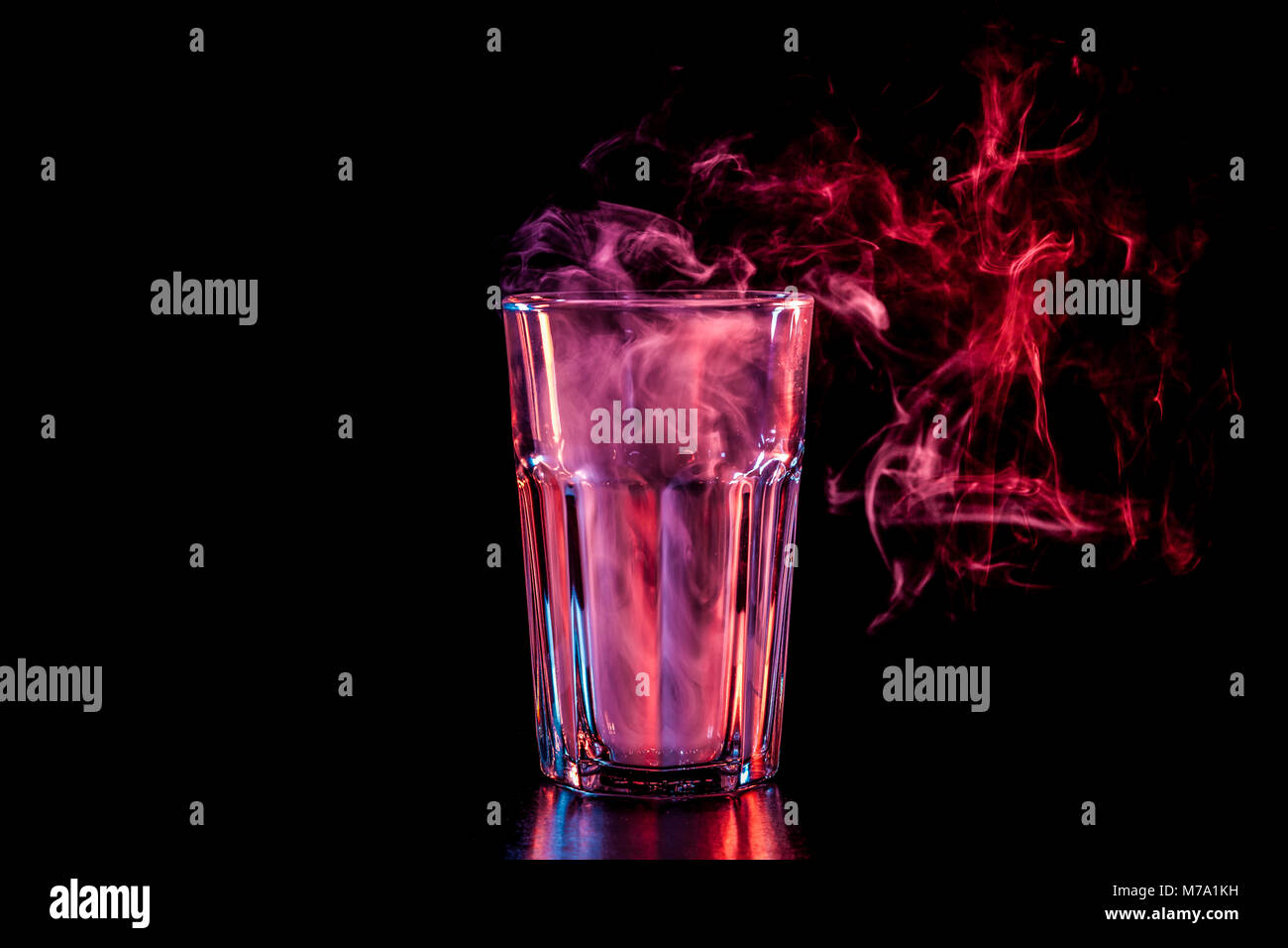 New glass with soft multi-colored red smoke from vape on a black ...