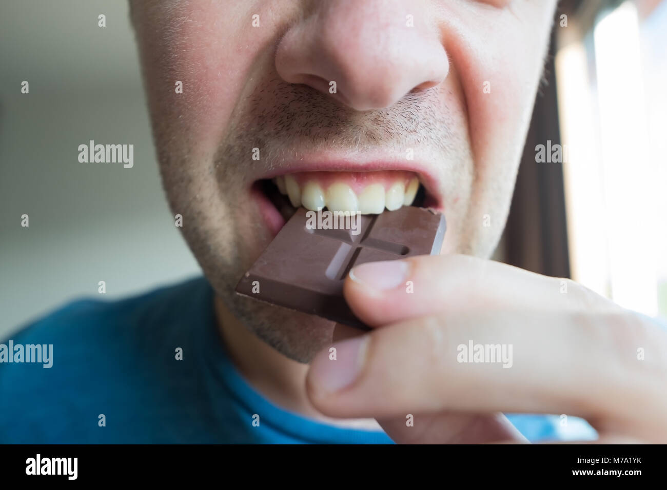 Young caucasian guy eating a chocolate alone at home Stock Photo - Alamy