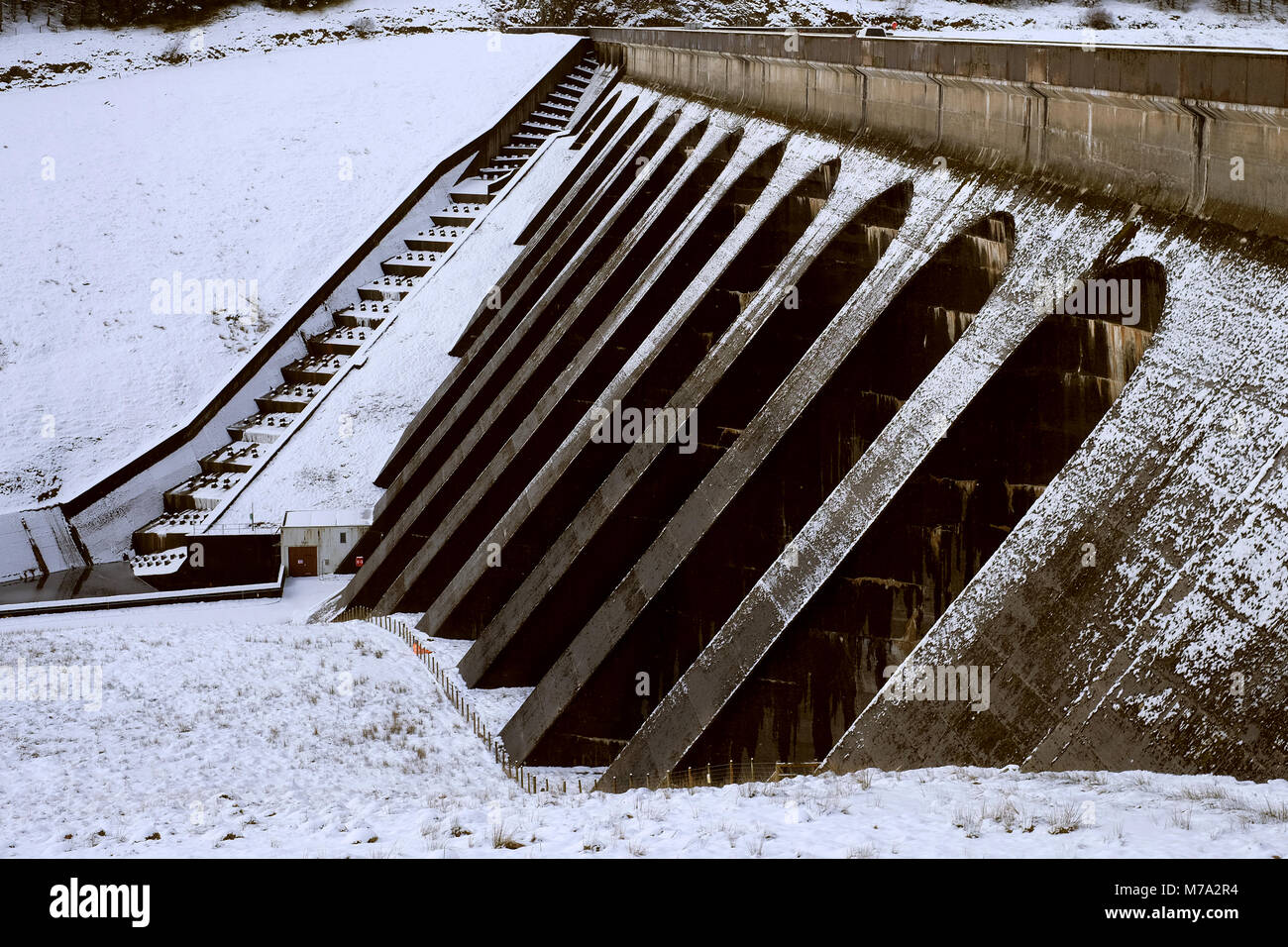 Nant y Moch reservoir dam buttresses and overflow in the snow Stock ...