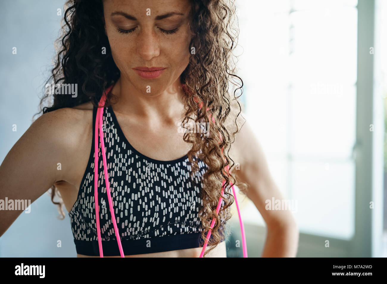 Fit young woman in sportswear looking tired standing alone in a gym ...