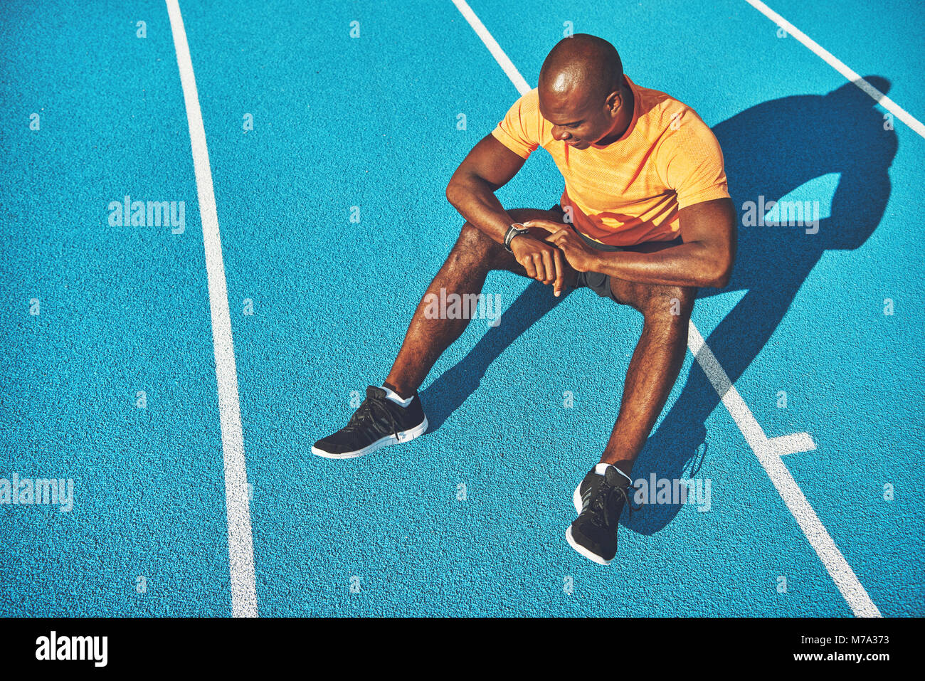Young African male athlete in sportswear sitting alone on the lanes of ...